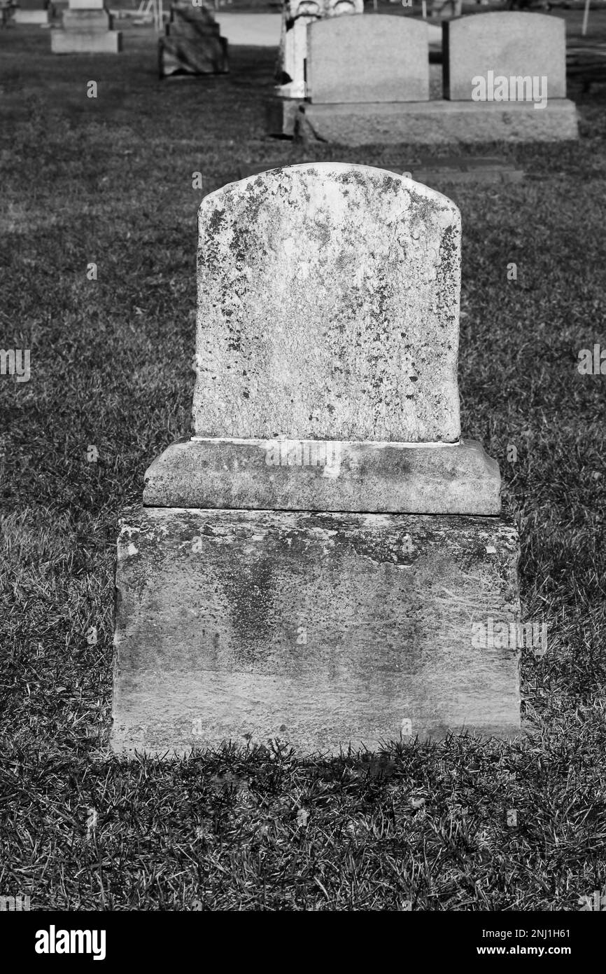 A worn and weathered old tombstone with a blank epitaph and room for ...