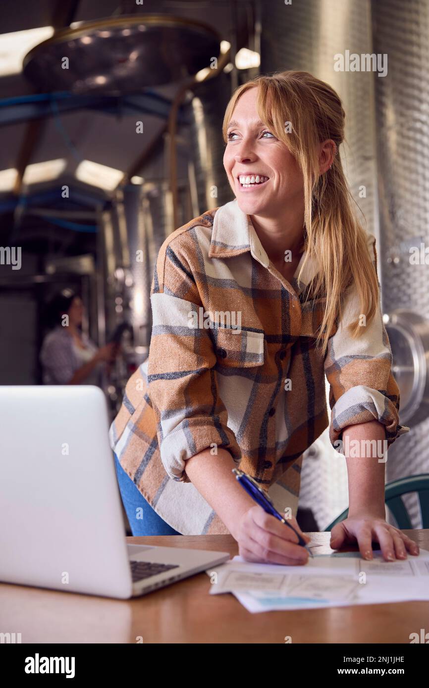 Woman With Laptop Making Notes By Bottle Label Inside Winery Stock ...