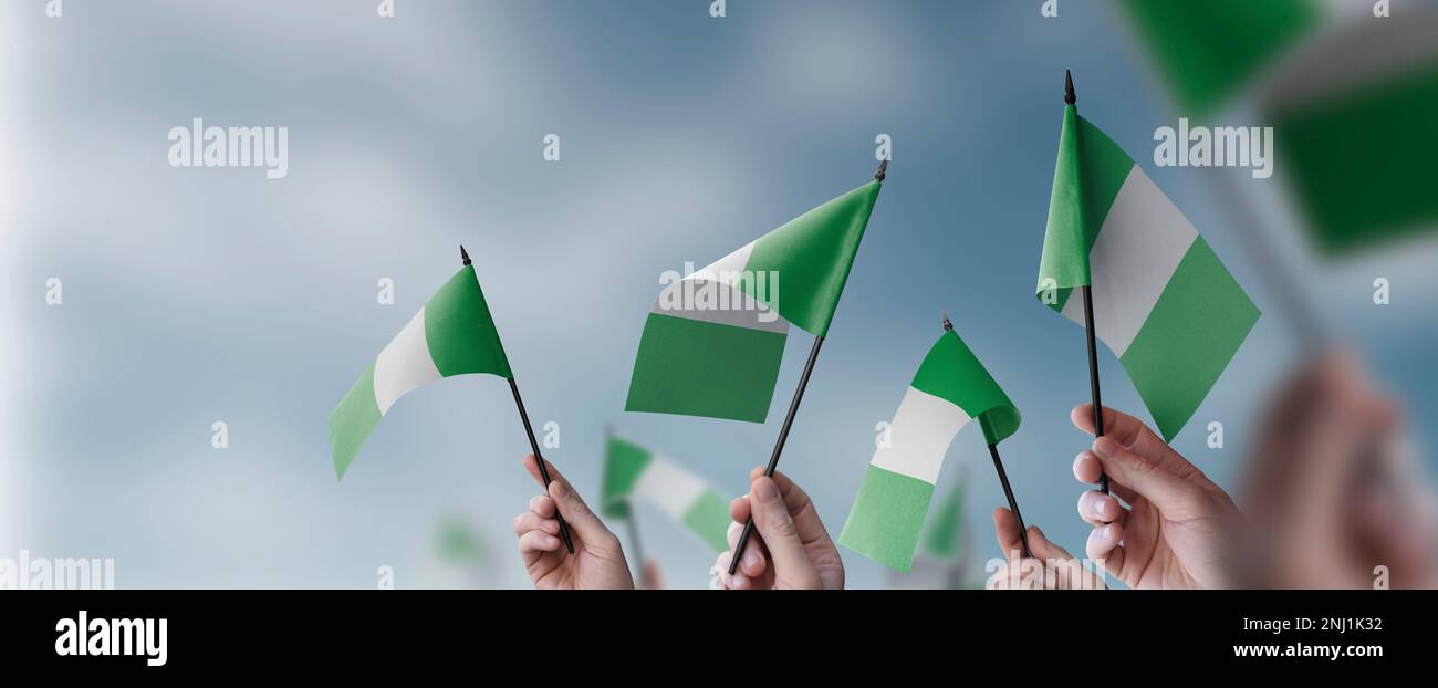 A group of people holding small flags of the Nigeria in their hands ...