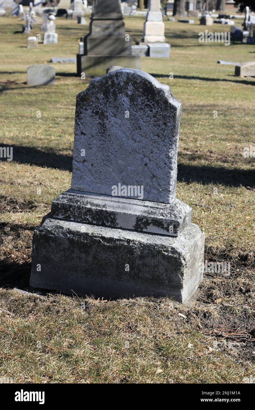 A worn and weathered old tombstone with a blank epitaph and room for ...