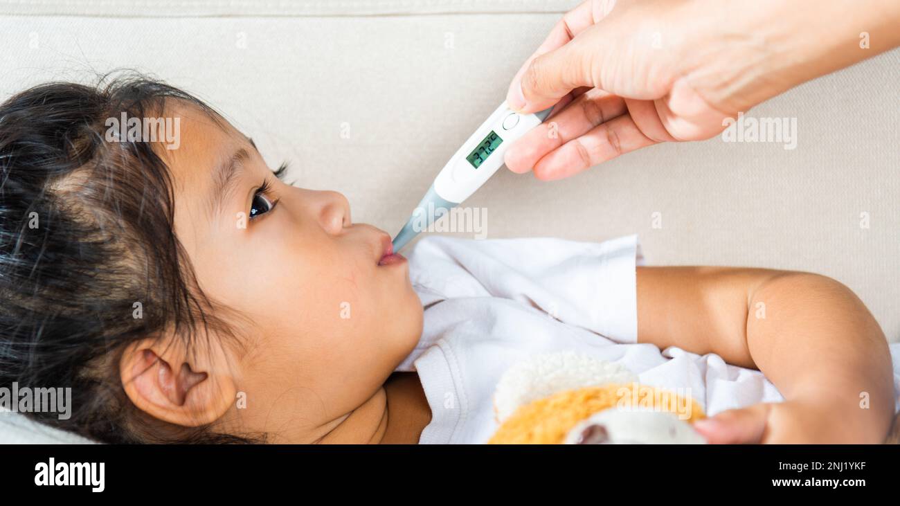 Mother parent checking temperature of her sick daughter with digital thermometer in mouth Stock ...