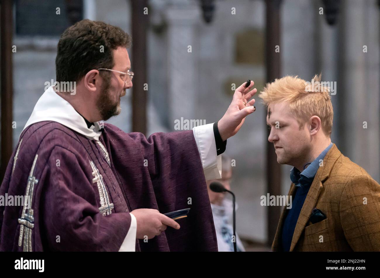 Canon Matthew Pollard makes an ash cross on the forehead of a member of ...