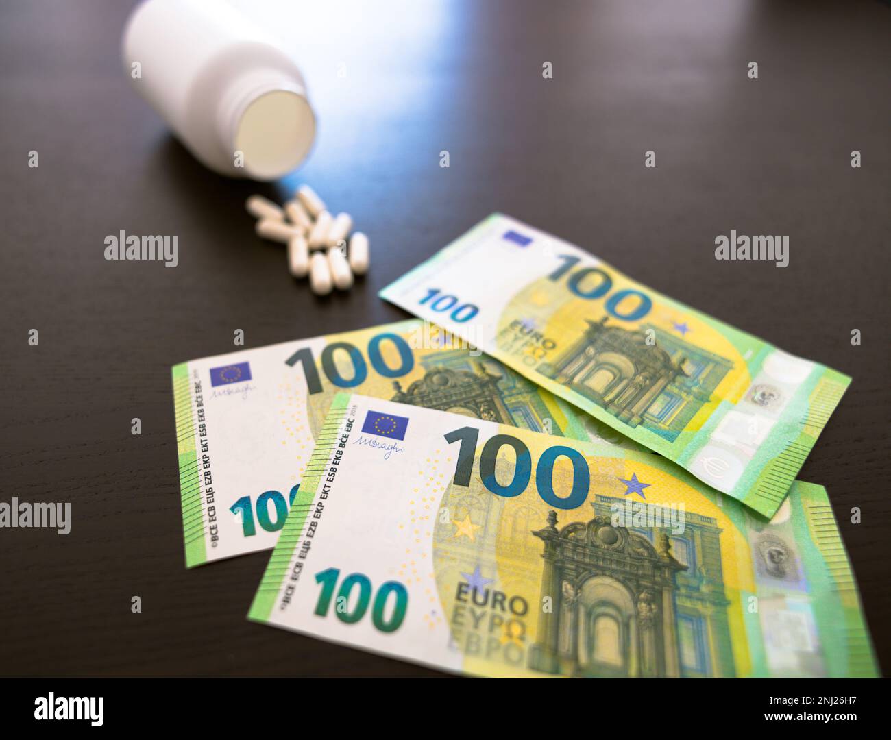 A jar of tablets on a black table. 100 euros in paper banknotes Stock ...