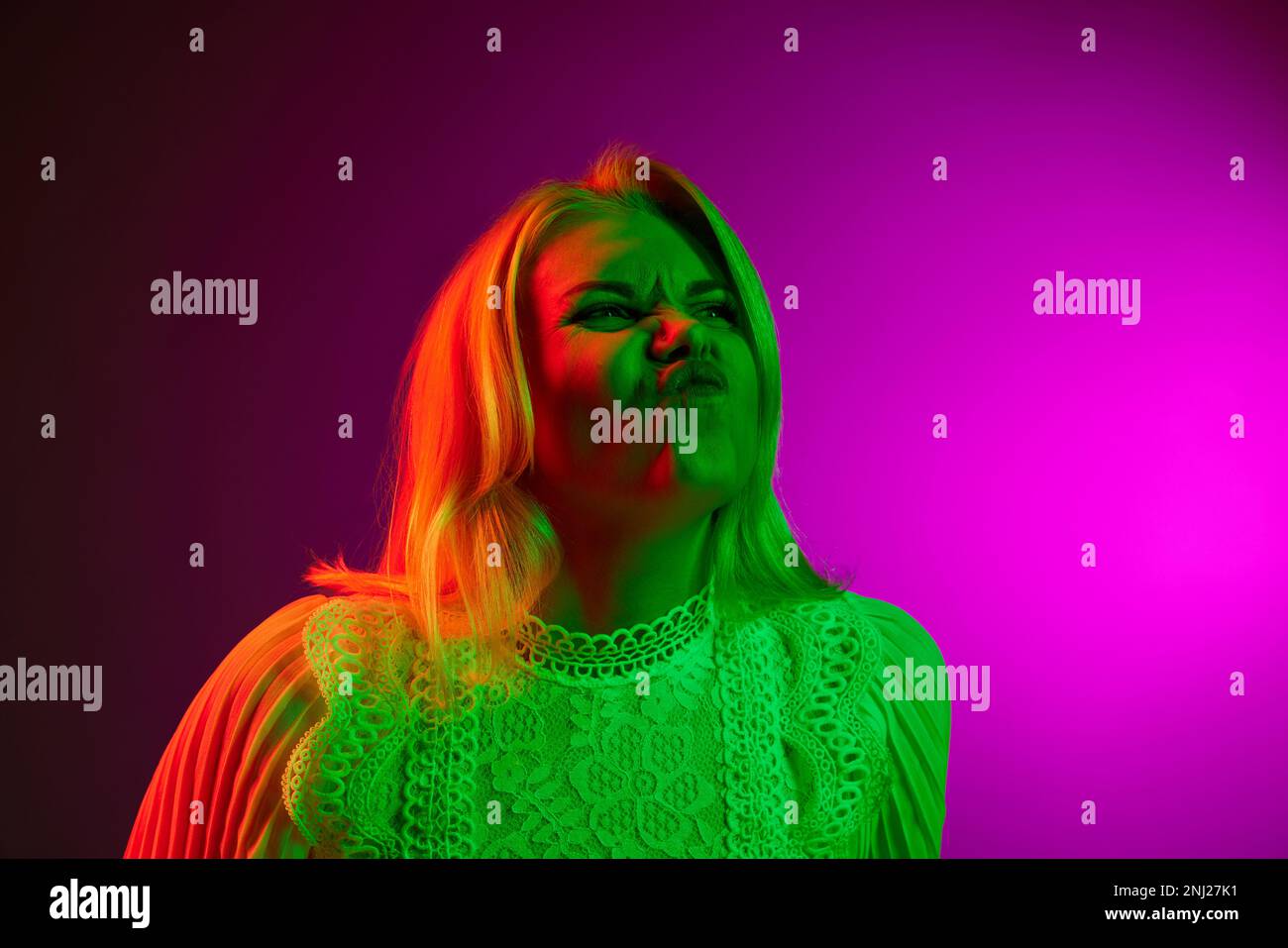 Funny face, grimacing. Young woman emotionally posing over magenta ...