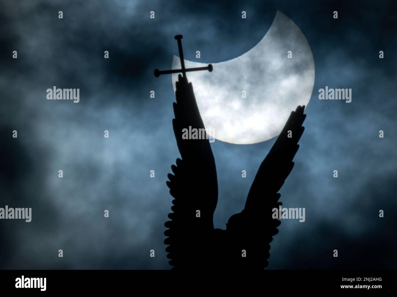 A partial solar eclipse can be seen above the gilded statue of ...