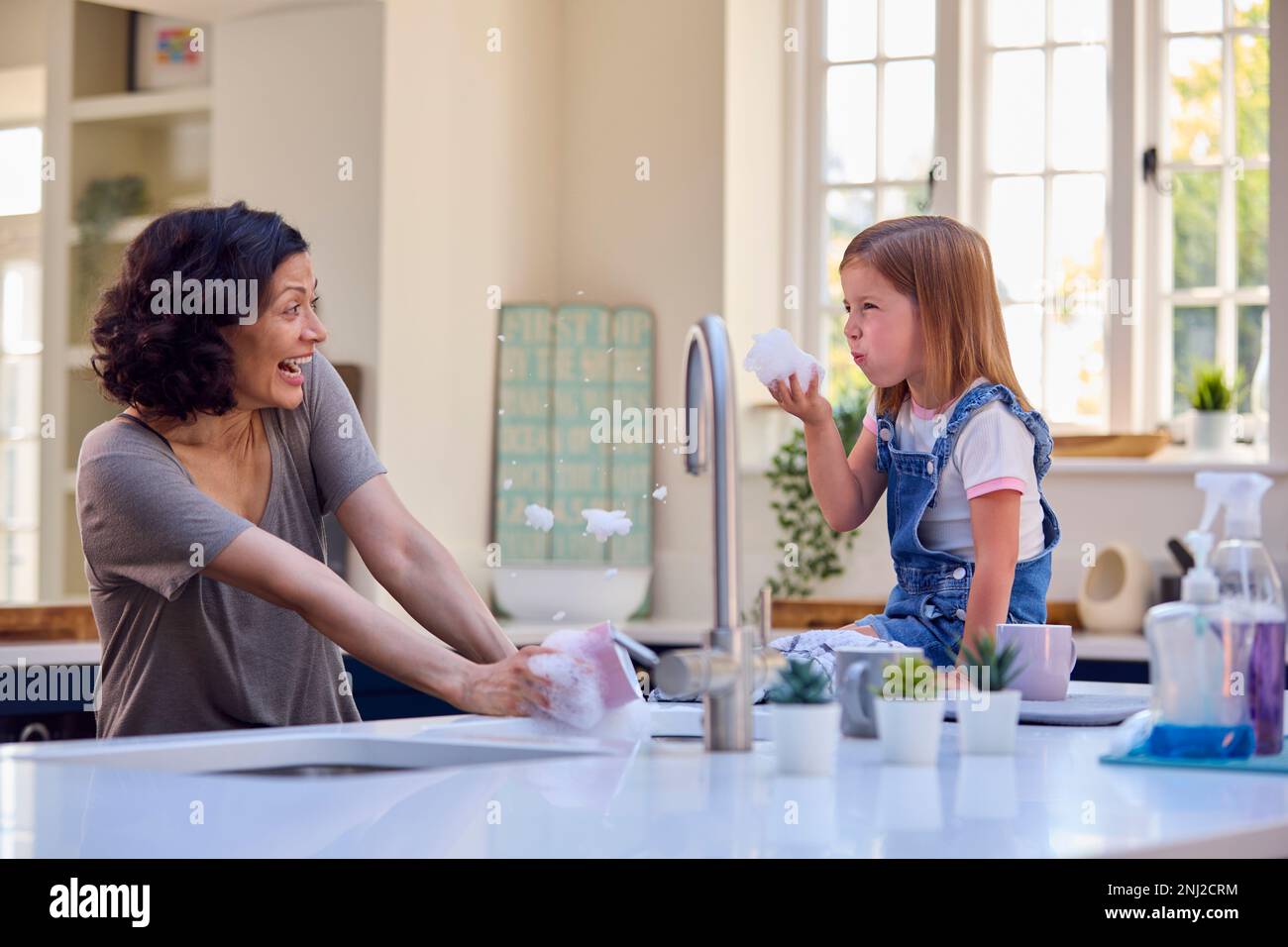 Family With Daughter Helping Older Mother To Do Washing Up In Kitchen ...