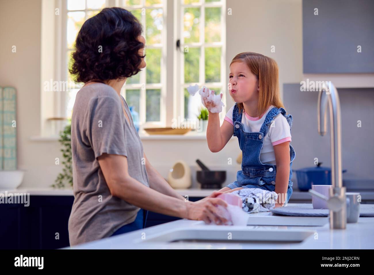 Family With Daughter Helping Older Mother To Do Washing Up In Kitchen ...