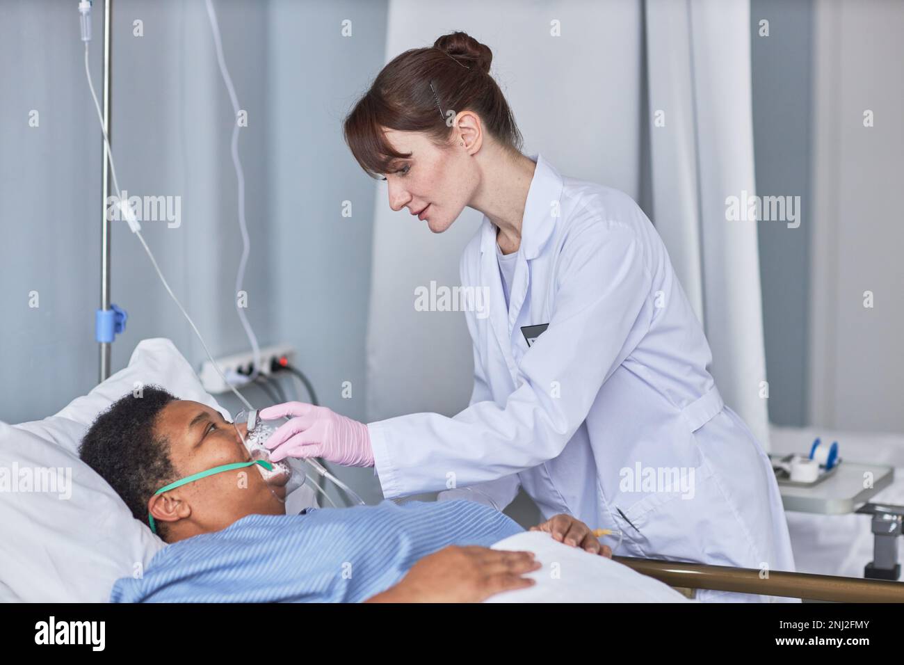 Side view portrait of caring nurse placing oxygen support mask on ...