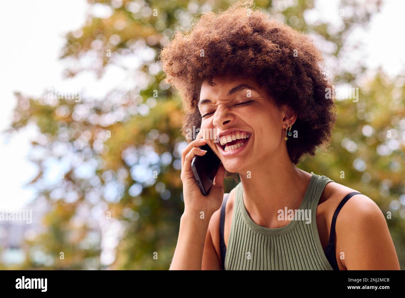 Smiling Young Woman Outdoors Laughing As She Talks On Mobile Phone ...