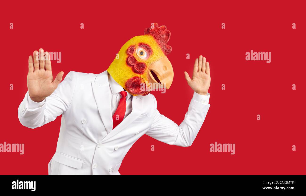 Crazy man in suit and funny chicken mask dancing isolated on red color ...
