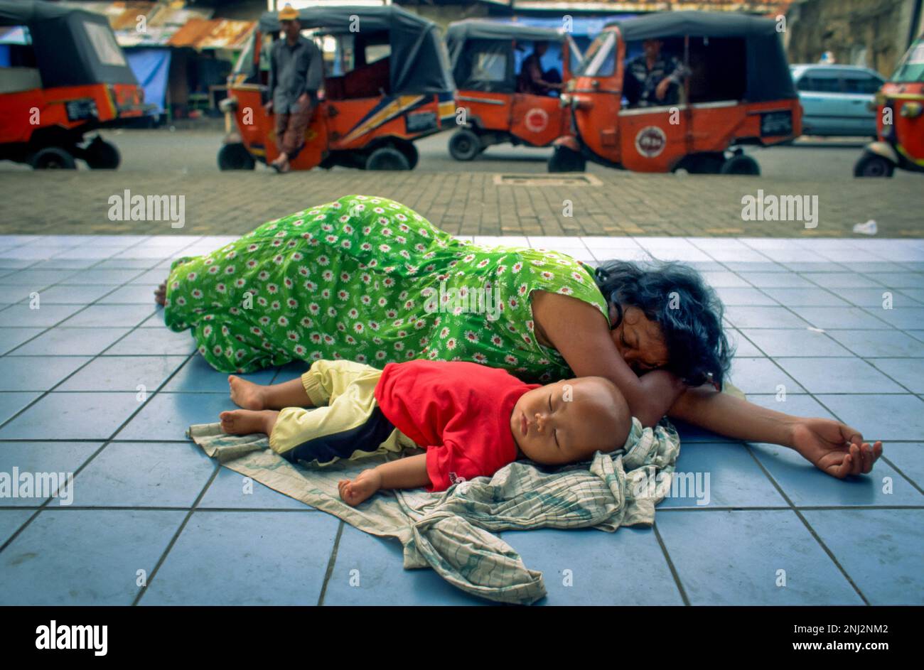 Indonesia, Jakarta. Homeless mother and child sleeping on the pavement ...