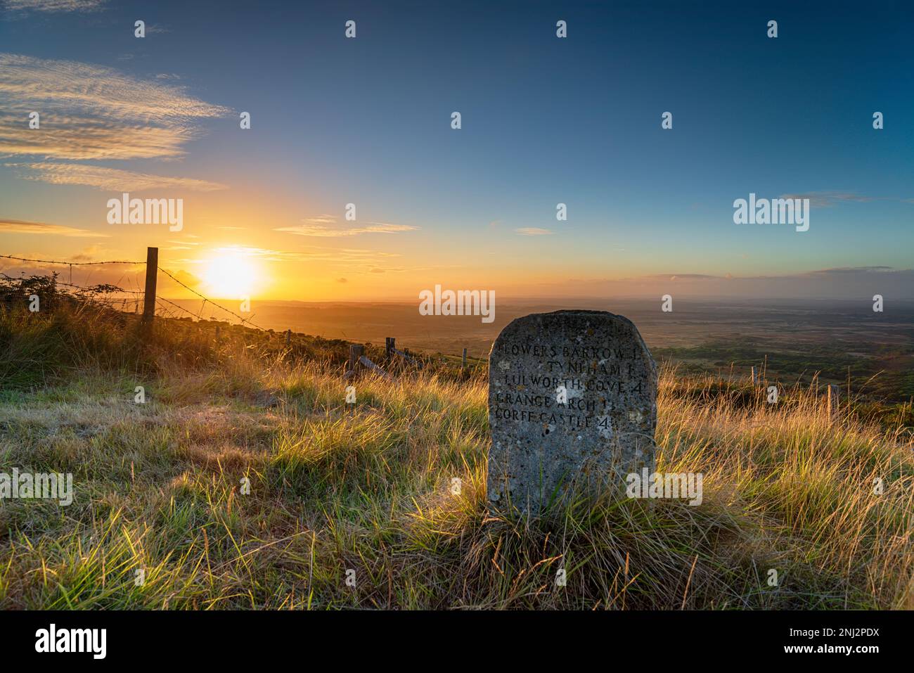 Sunset over a waymarker stone on the Lulworth ranges near Tyneham in ...