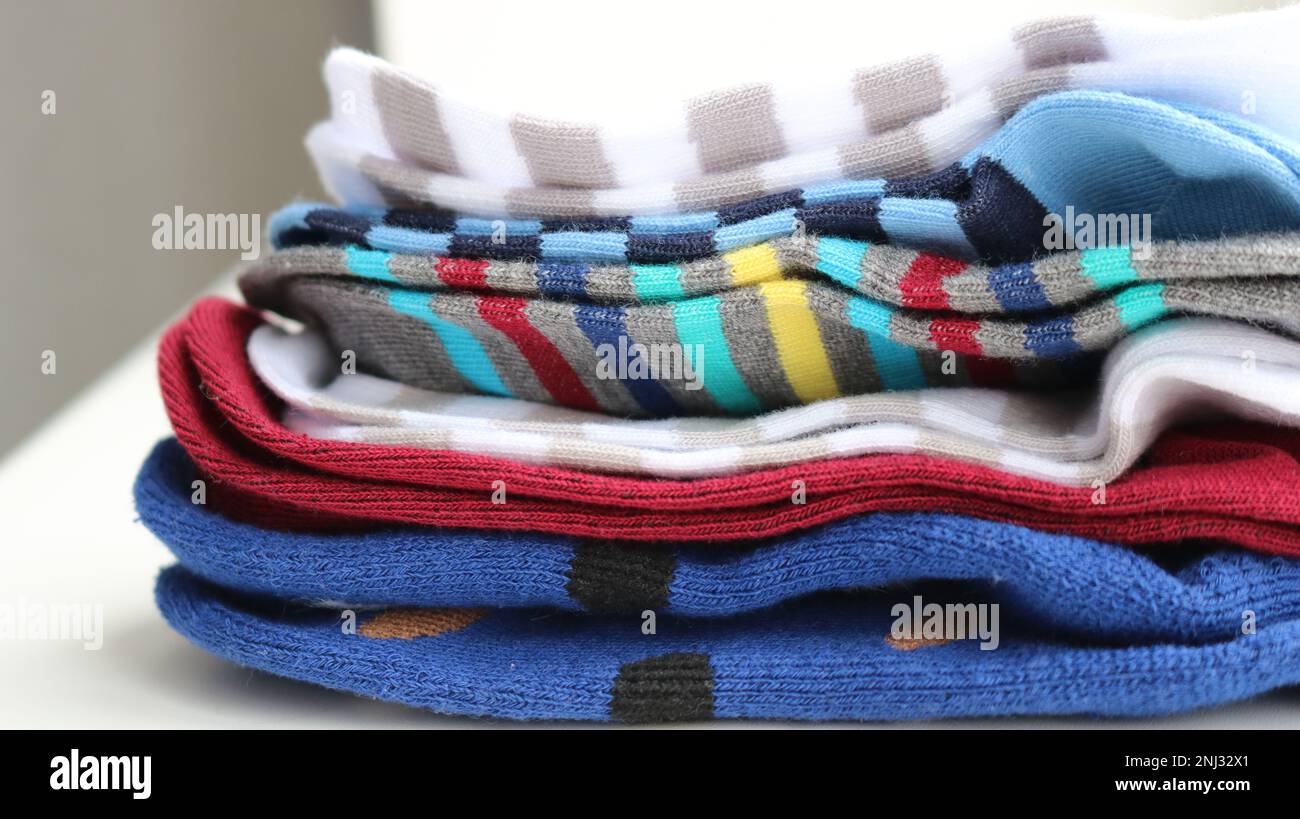 a stack of striped multi-colored children's socks lying on a light ...