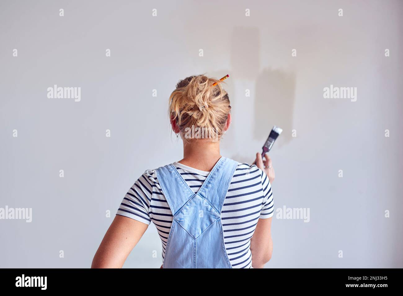 Rear View Of Woman Decorating Room In House Painting Tester Paint ...