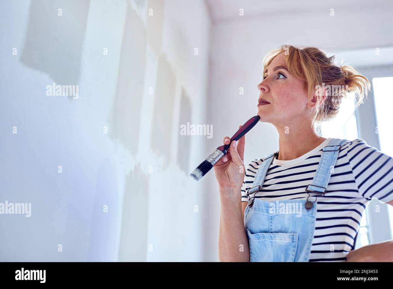 Woman Decorating Room In House Painting Tester Paint Colour Strips On ...