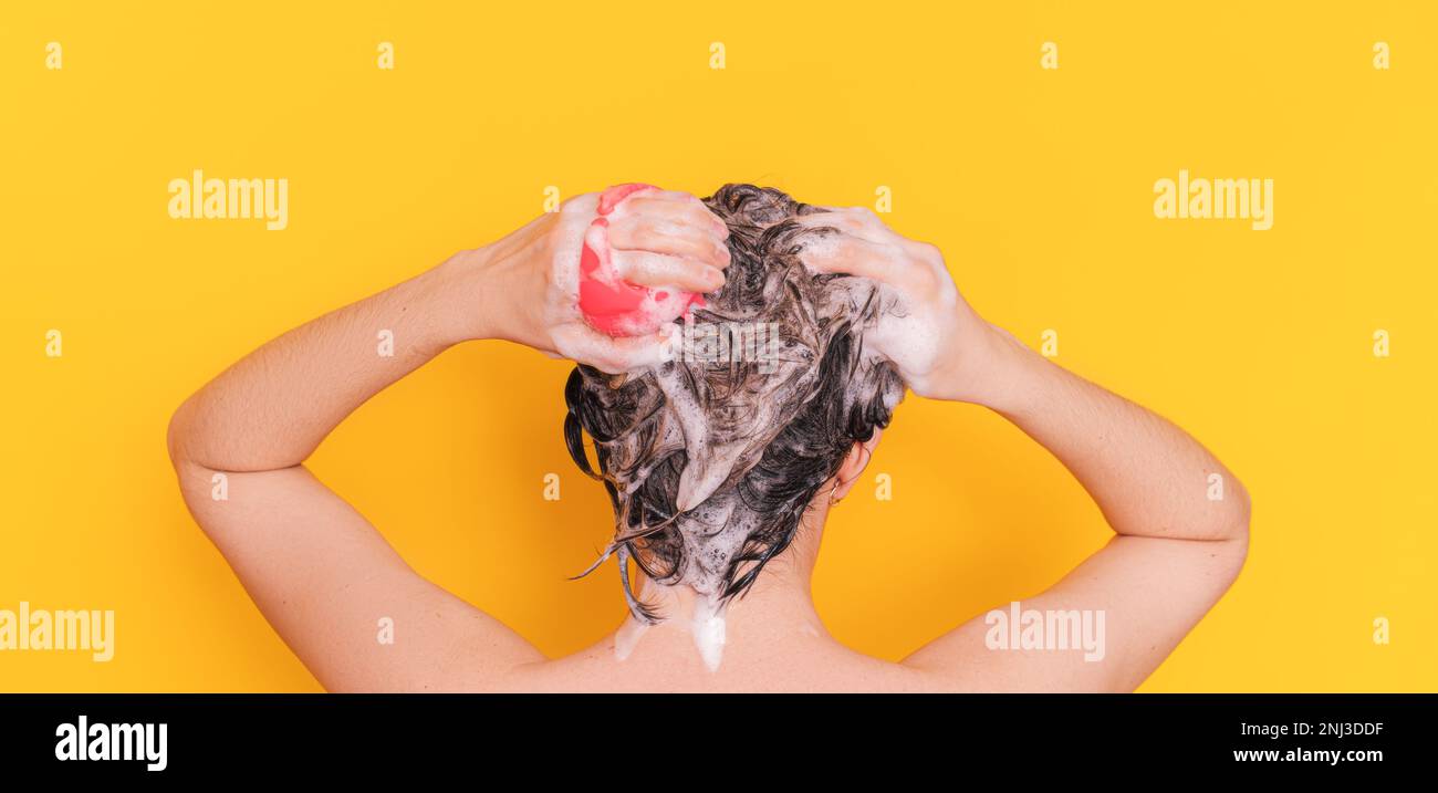 Lady with foam in her hair takes care of her scalp with pink color ...