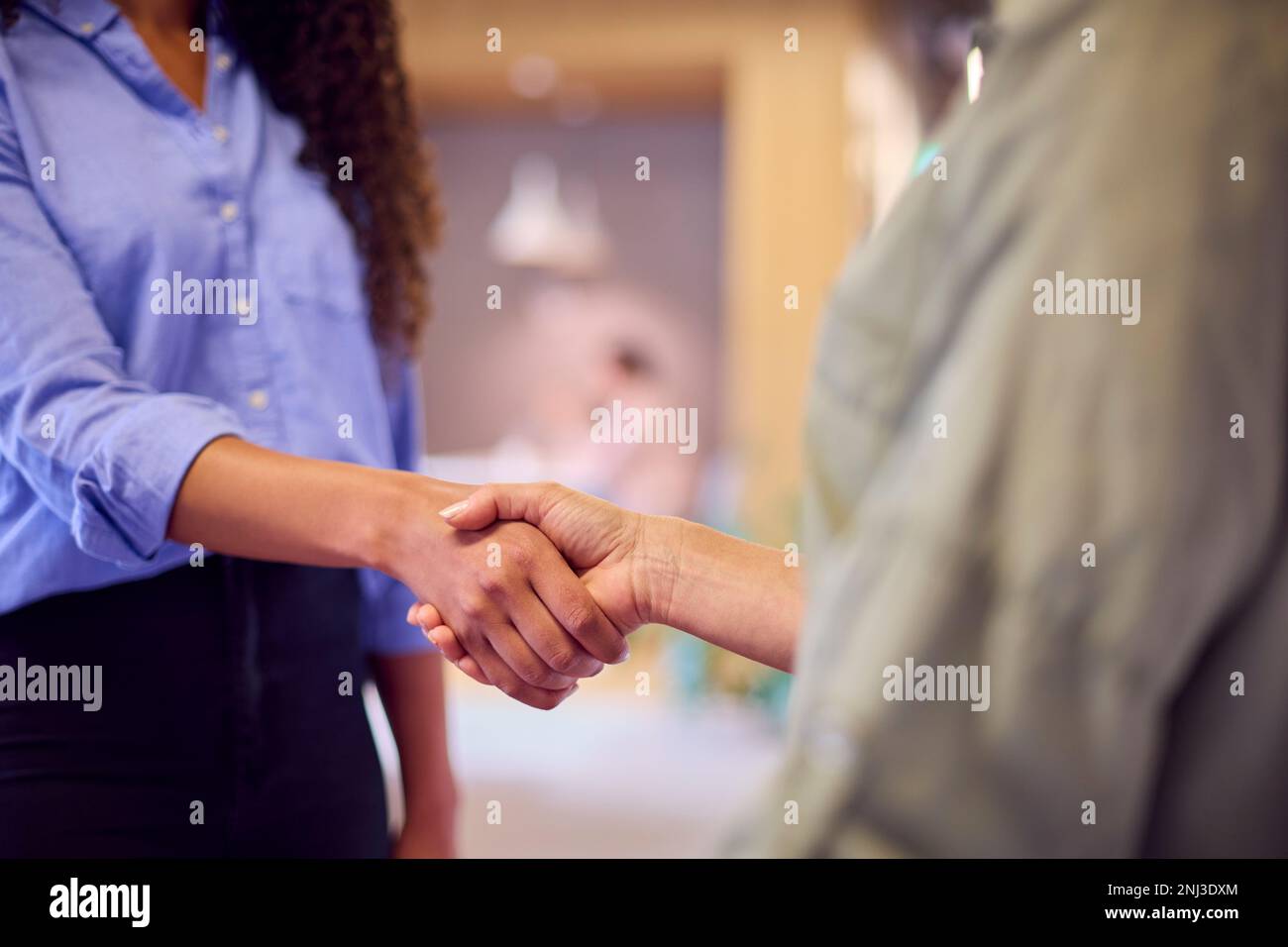 Close Up Of Two Businesswomen Meeting And Shaking Hands In Modern Open ...
