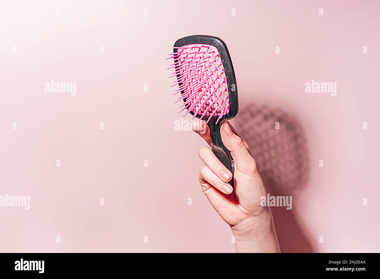 Pink comb in female hand against pink background Stock Photo - Alamy