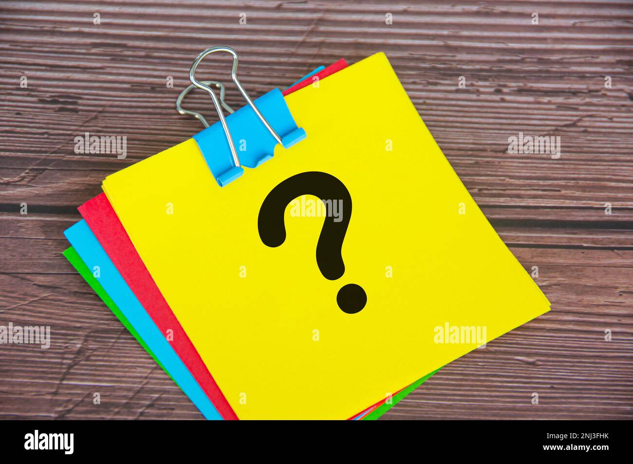 Question mark on yellow notepad with wooden desk background ...