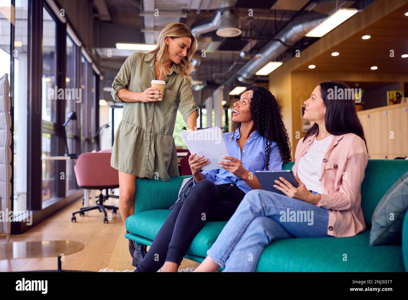 Businesswomen Having Informal Meeting In Breakout Seating Area Of ...