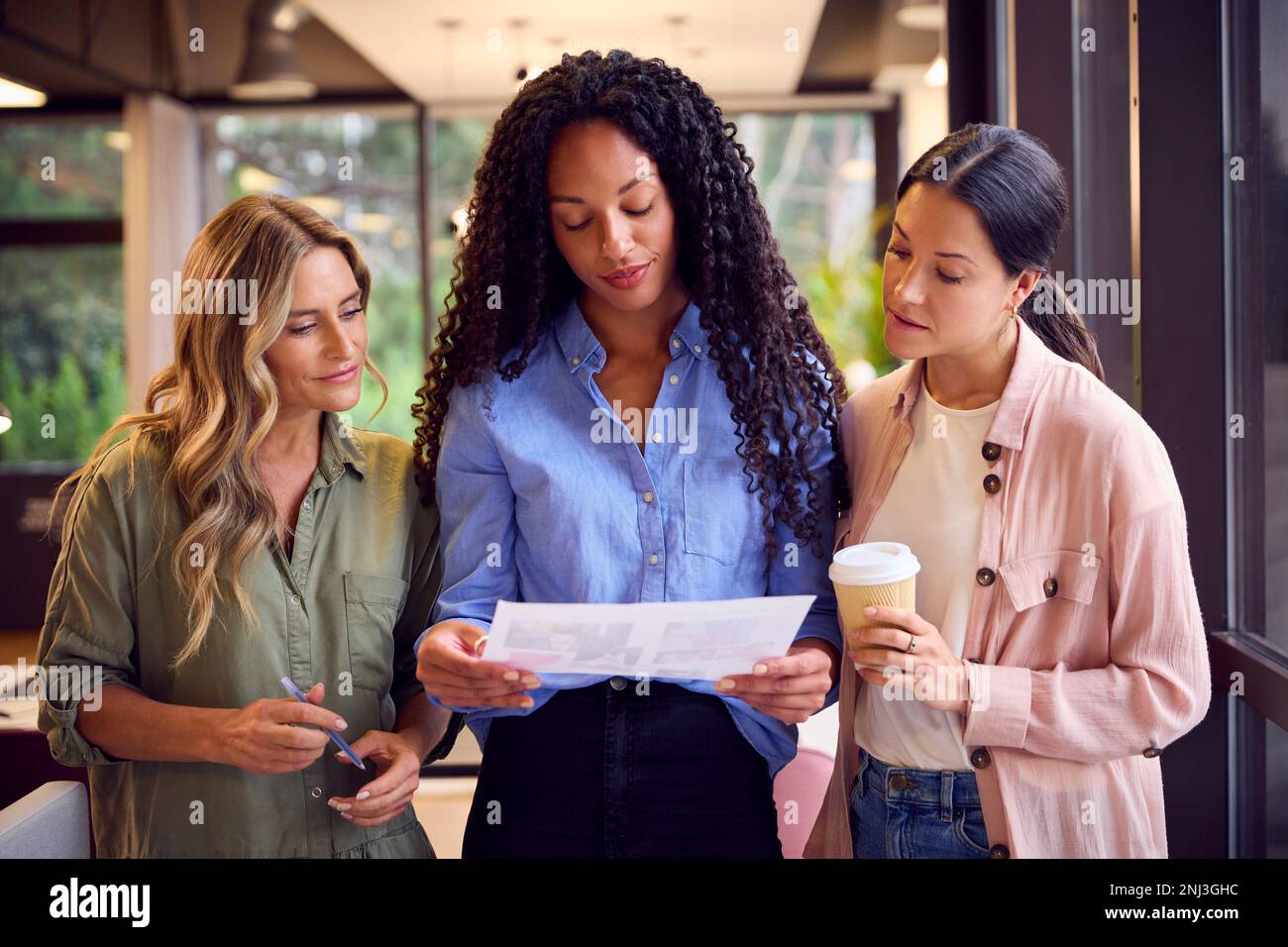 Female Business Team Stand At Desk In Open Plan Office Approving ...