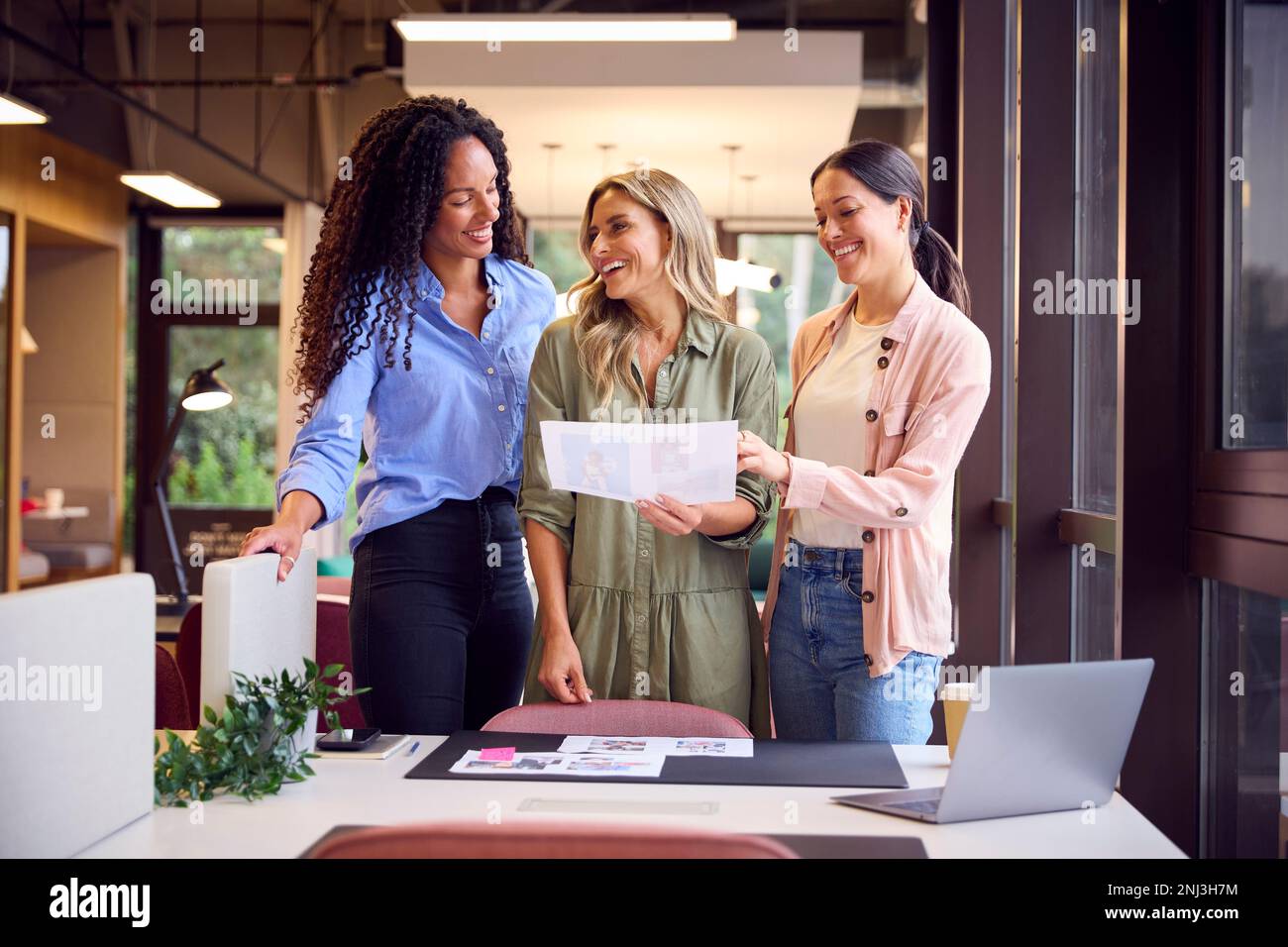 Female Business Team Stand At Desk In Open Plan Office Approving ...