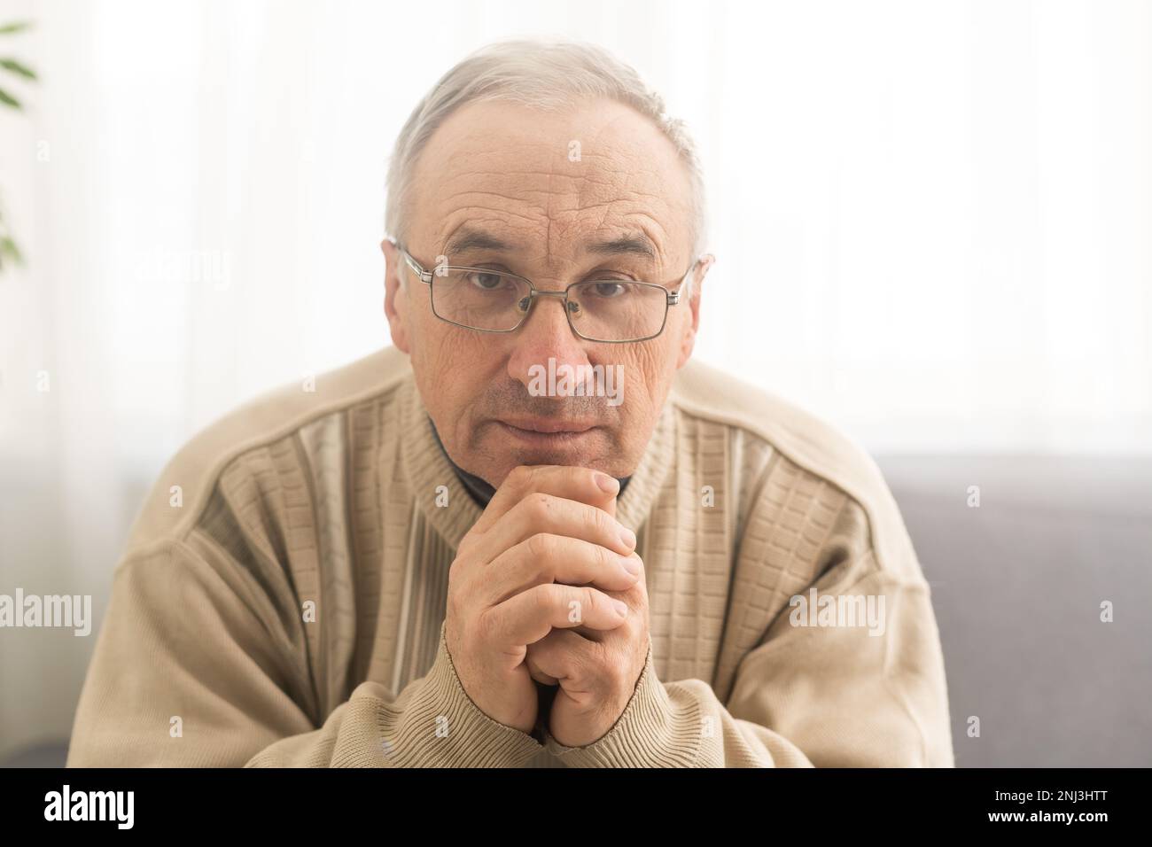 Please, Lord. Nervous worried aged Caucasian man praying on couch at ...