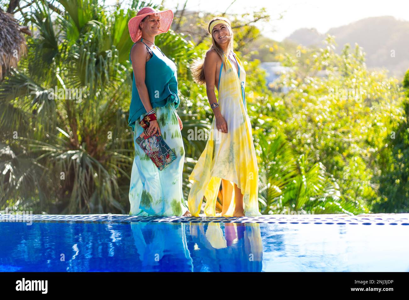 Female models standing on the edge of an outdoor tropical pool Stock ...