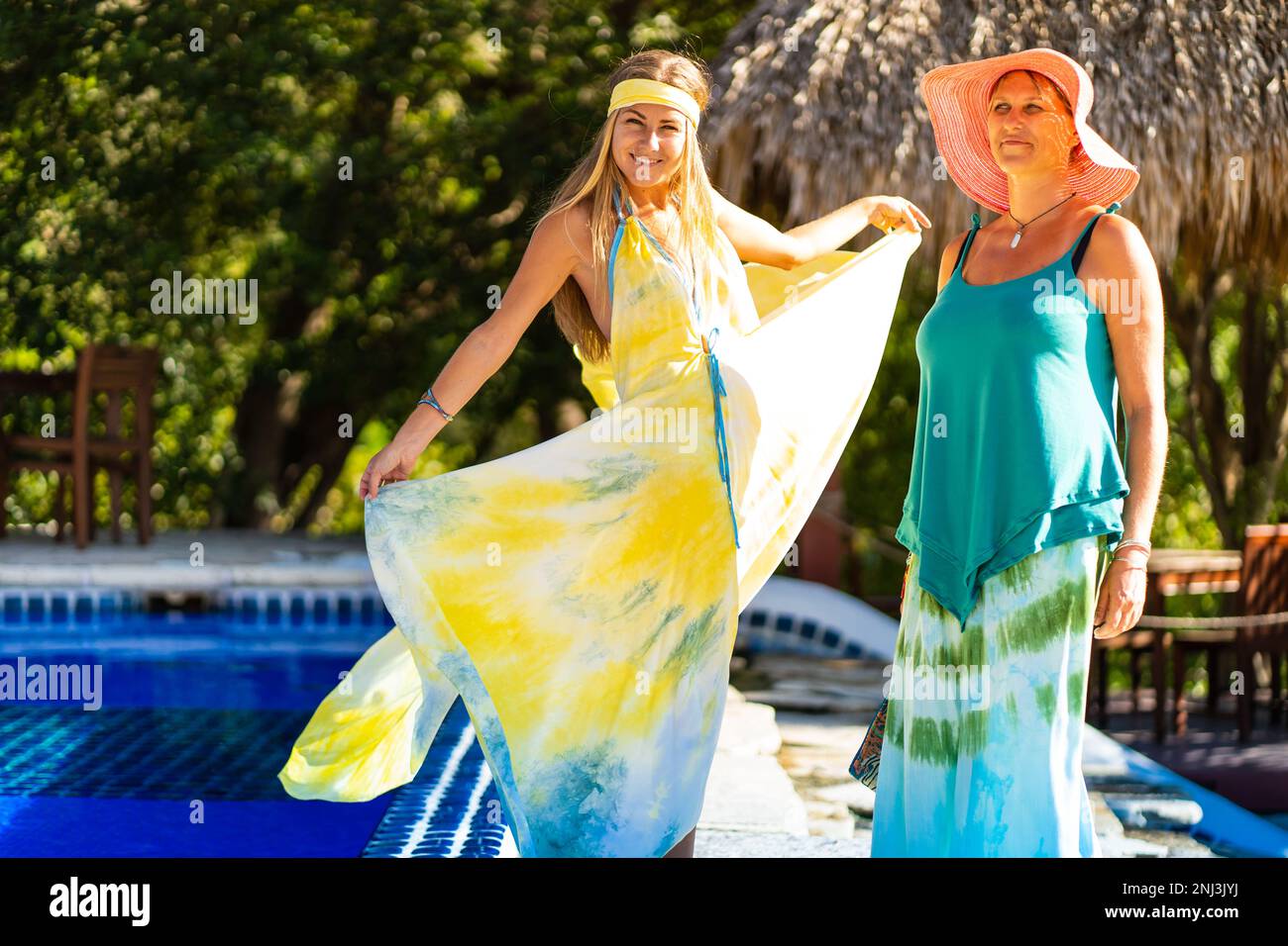 Models dancing and standing on the edge of an outdoor tropical pool ...
