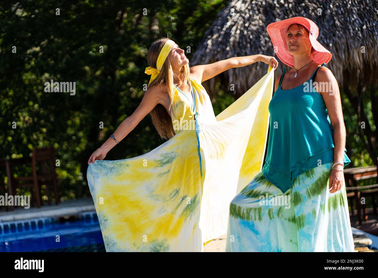 Models performing on the edge of an outdoor tropical pool wearing long ...
