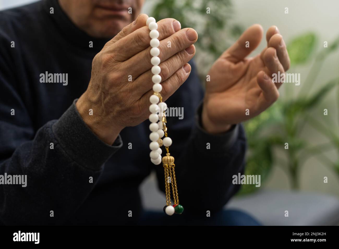 Praying hands of an old man holding rosary beads Stock Photo - Alamy