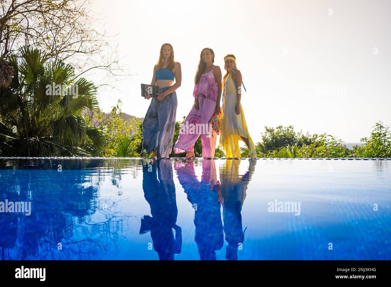 Three models with long colorful dresses standing on the edge of an ...