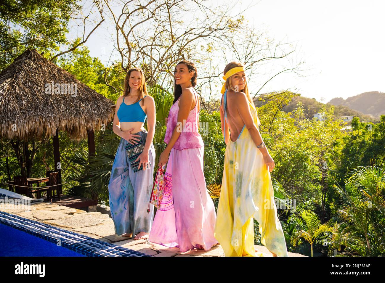 Three women with long dresses standing on the edge of an outdoor ...