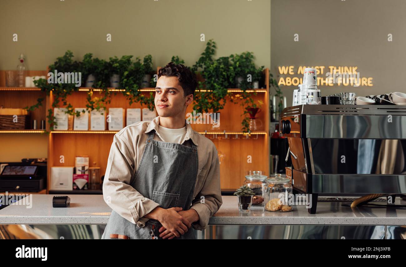 Confident local coffee shop owner leaning counter wearing an apron ...