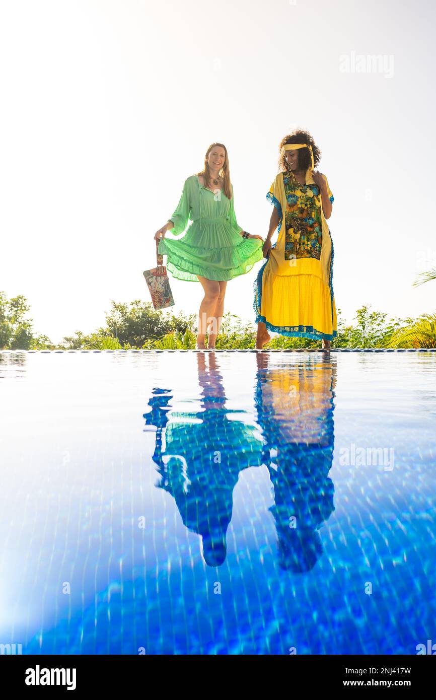 Vertical photo of two models with colorful dress posing next to an ...