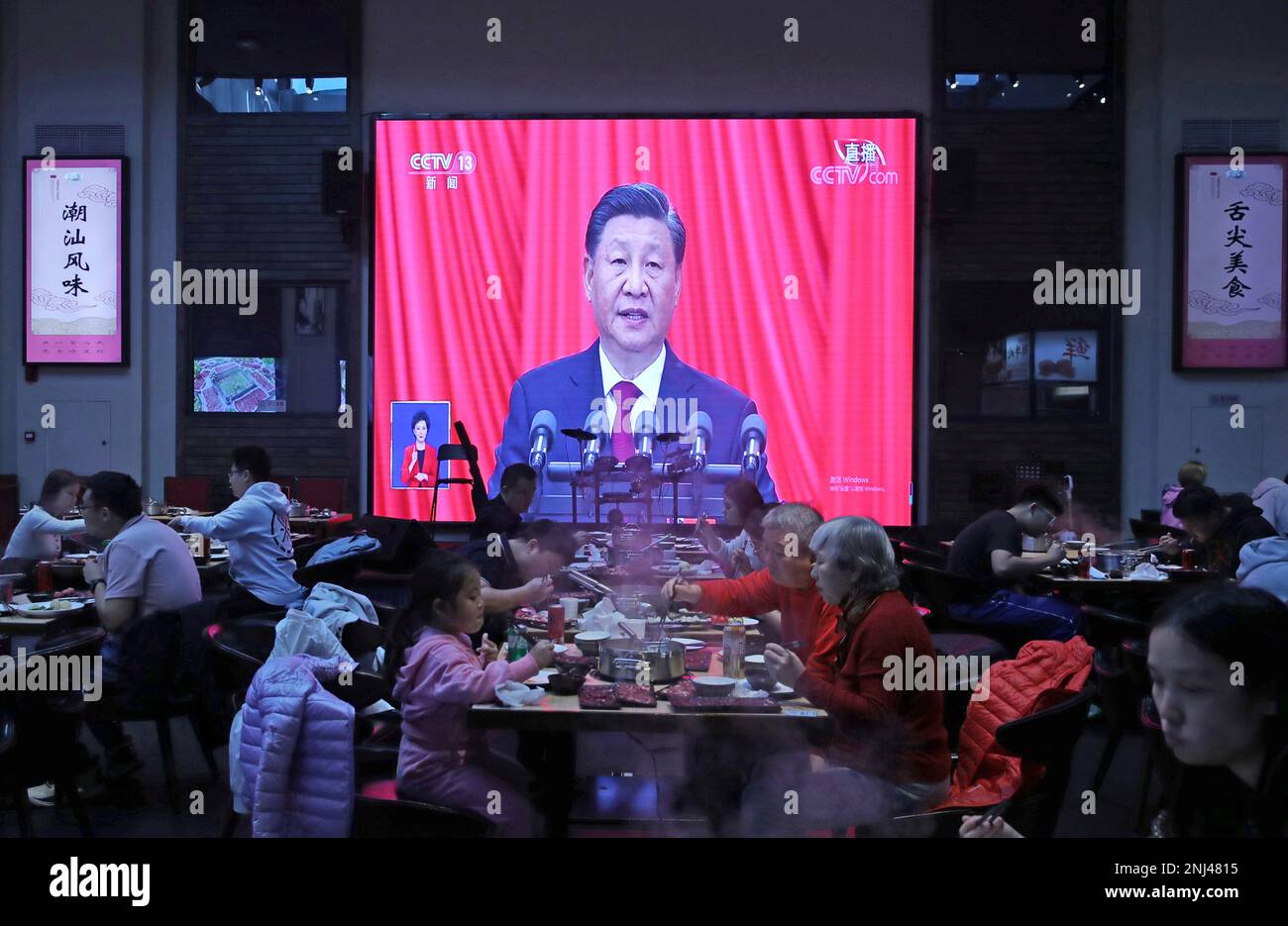 A monitor shows China's President Xi Jingpin delivering a political ...