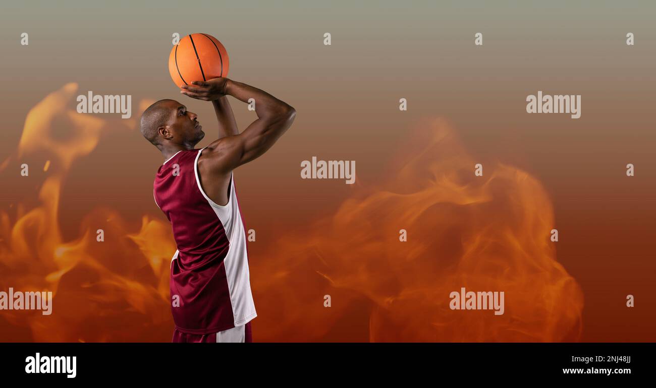 Composition of male basketball player shooting ball, over flames on ...