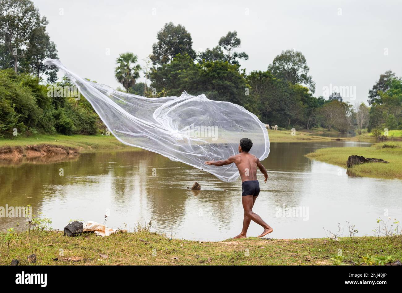 A villager in Cambodia's Siem Reap province throws his fishing net to ...