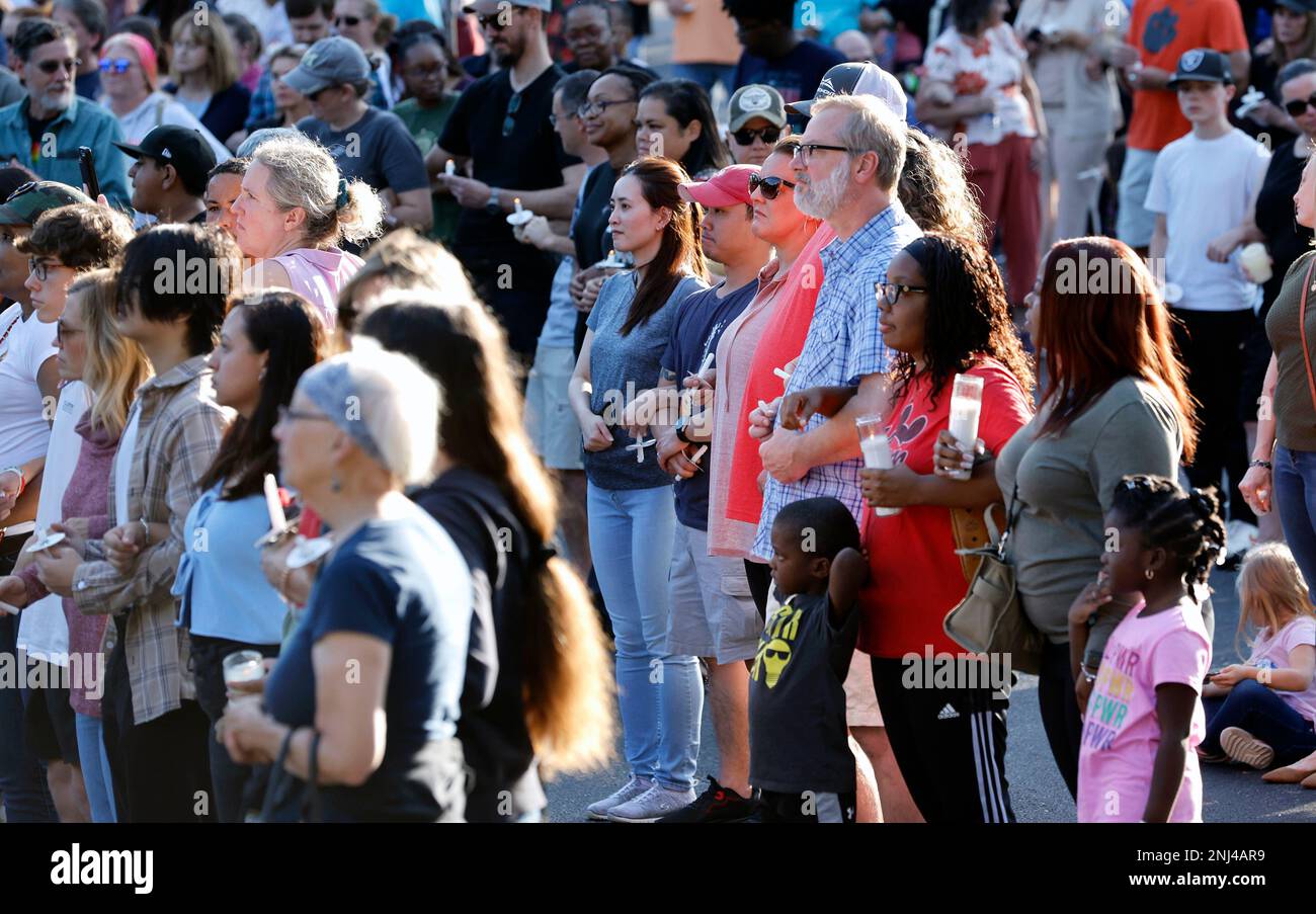 Attendees lock arms together in unity during a candlelight vigil ...