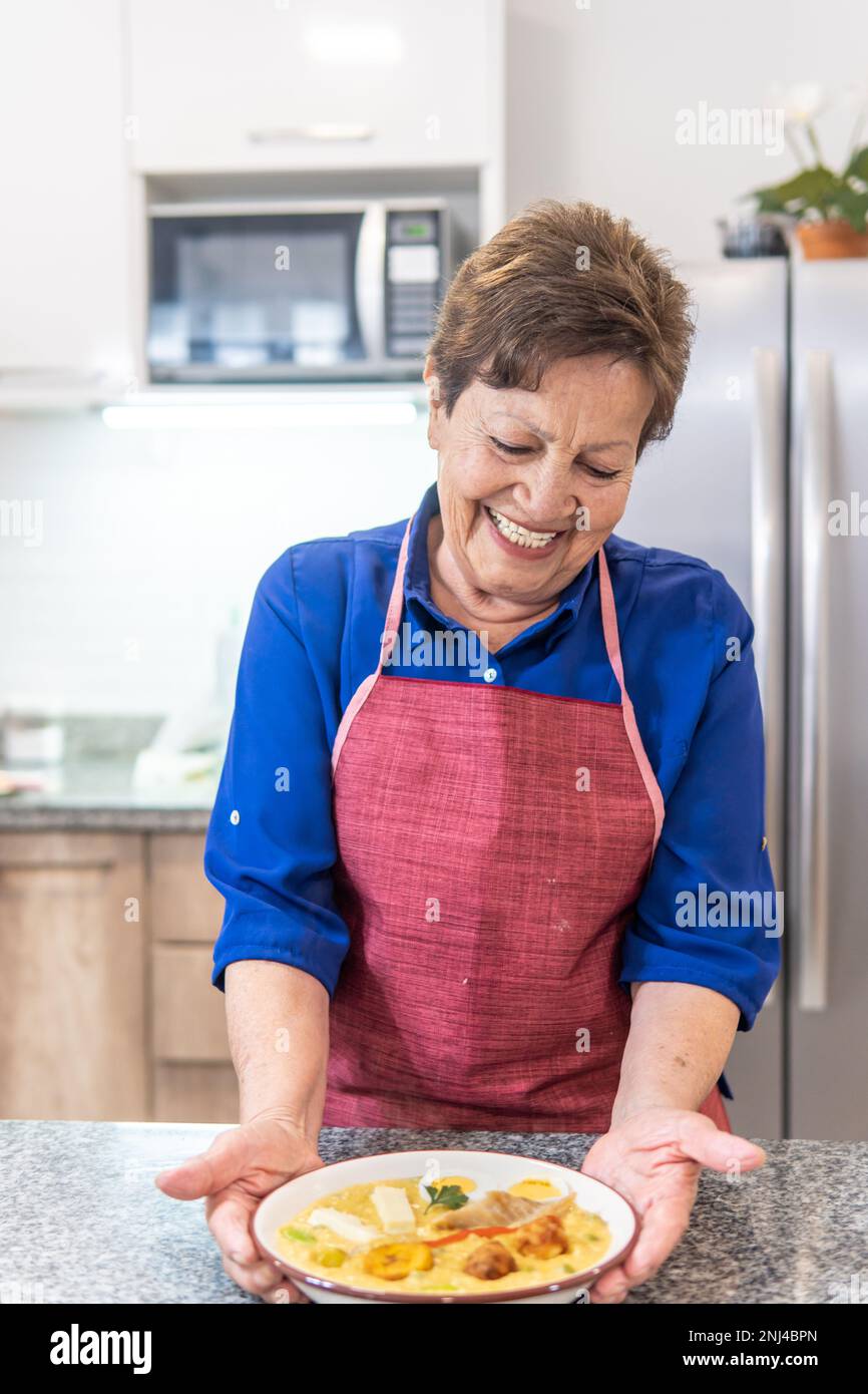 Granny smiling serving soup in the kitchen Stock Photo - Alamy