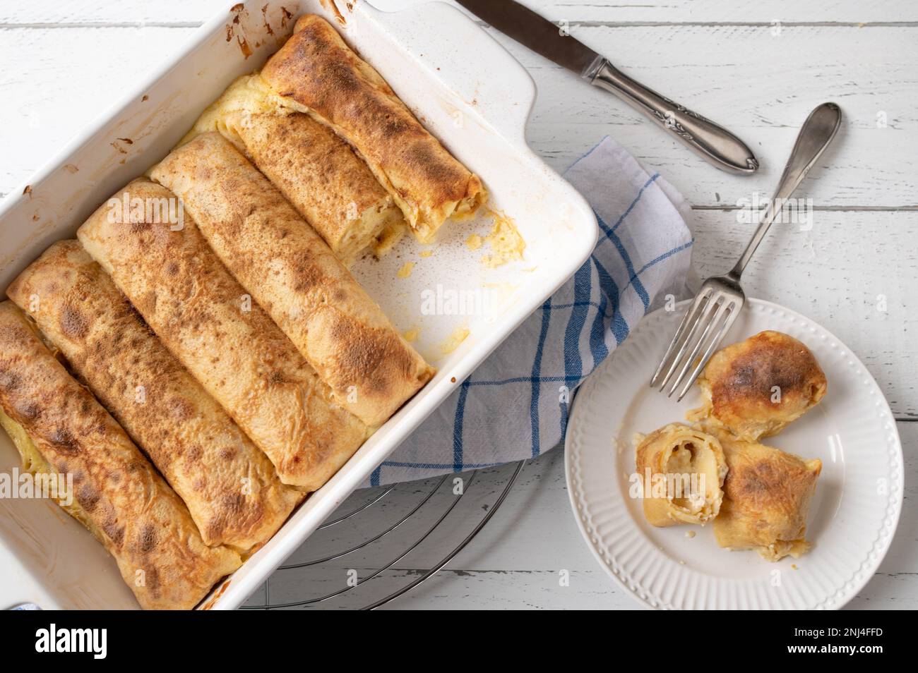 Filled pancake rolls with quark lemon filling in a baking dish on white ...