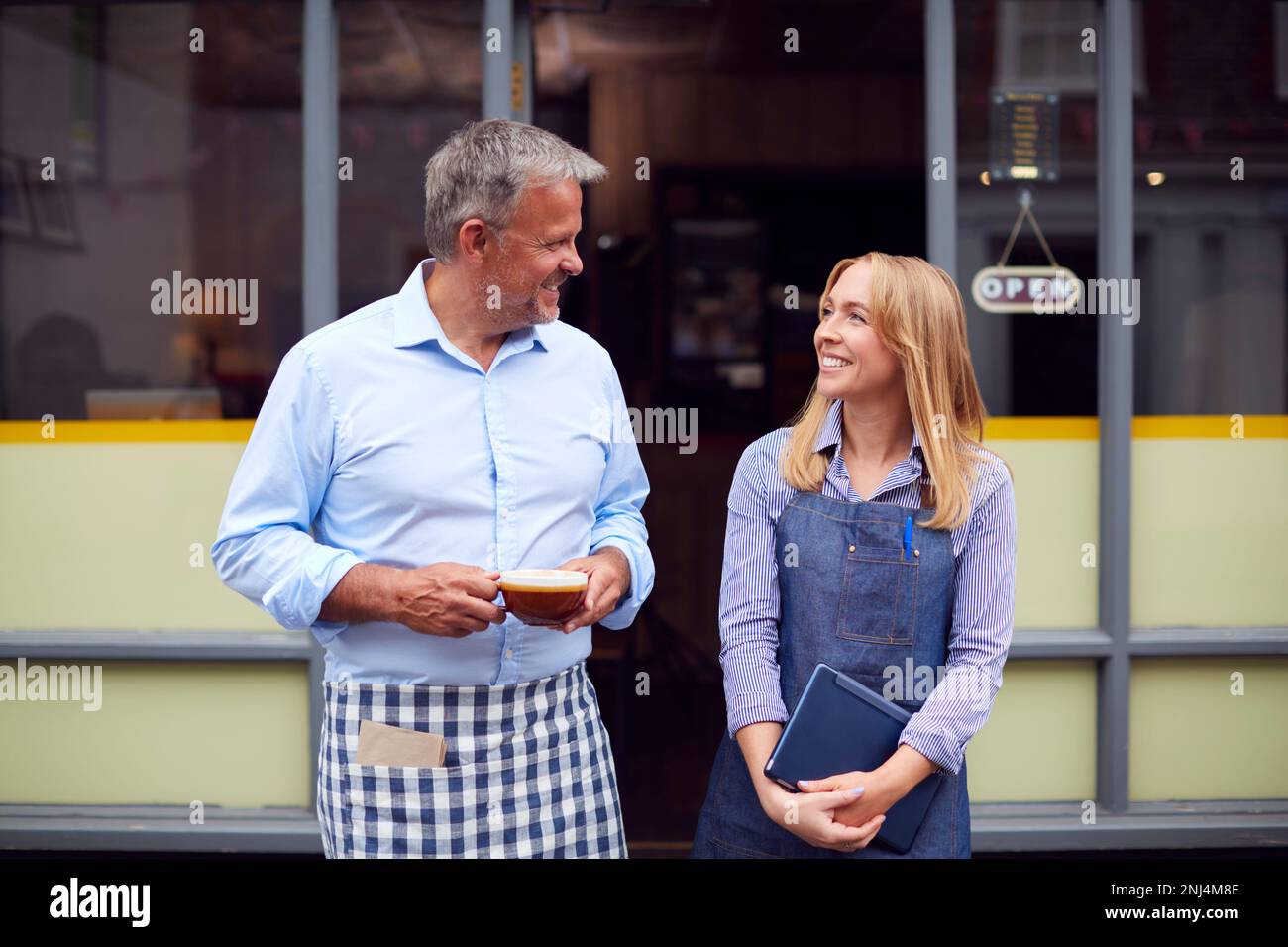 Male And Female Owners Or Staff Standing Outside Coffee Shop With ...