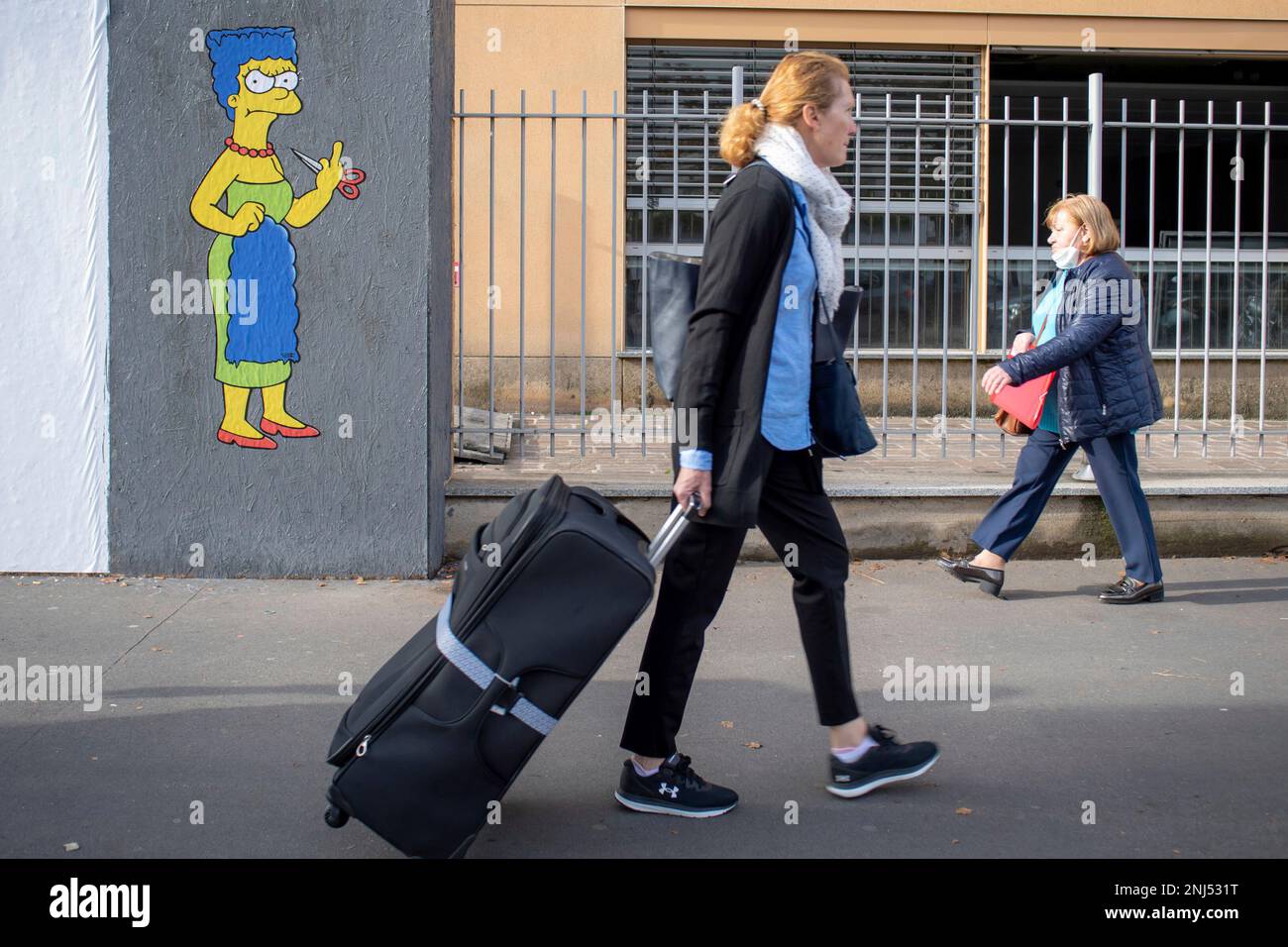 Women walk past a mural called "The Cut" by street artist aleXsandro ...