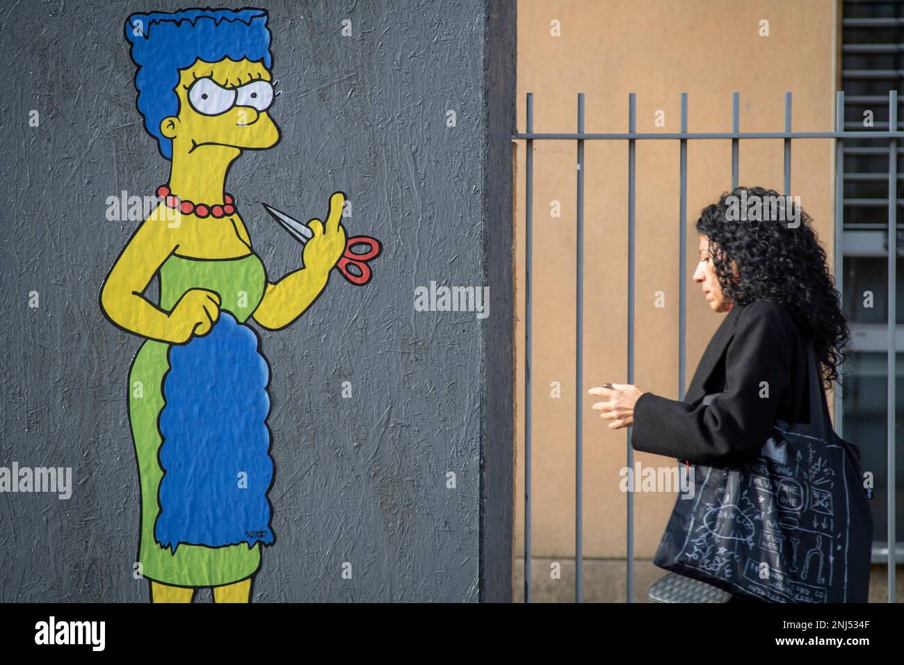 A woman walks past a mural called "The Cut" by street artist aleXsandro ...