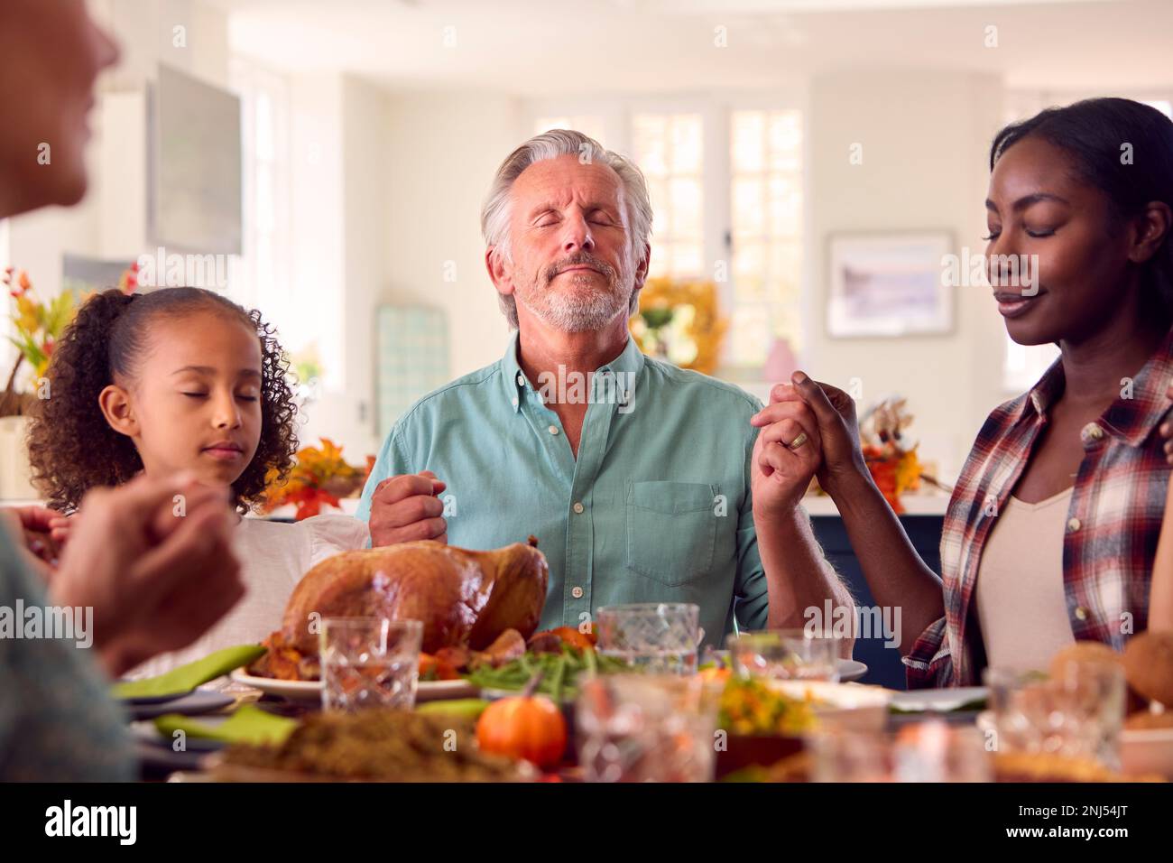 Multi-Generation Family Celebrating Thanksgiving At Home Saying Prayer ...