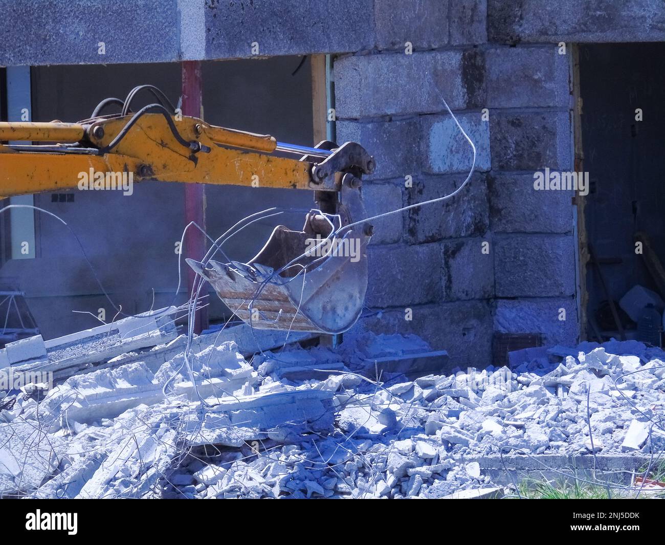 Bucket of a hydraulic excavator collects the rubble after a demolition ...