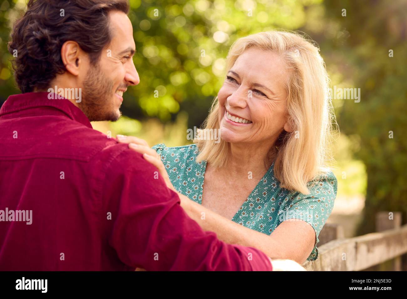 Mature Mother With Mixed Race Adult Son Leaning On Fence Walking In