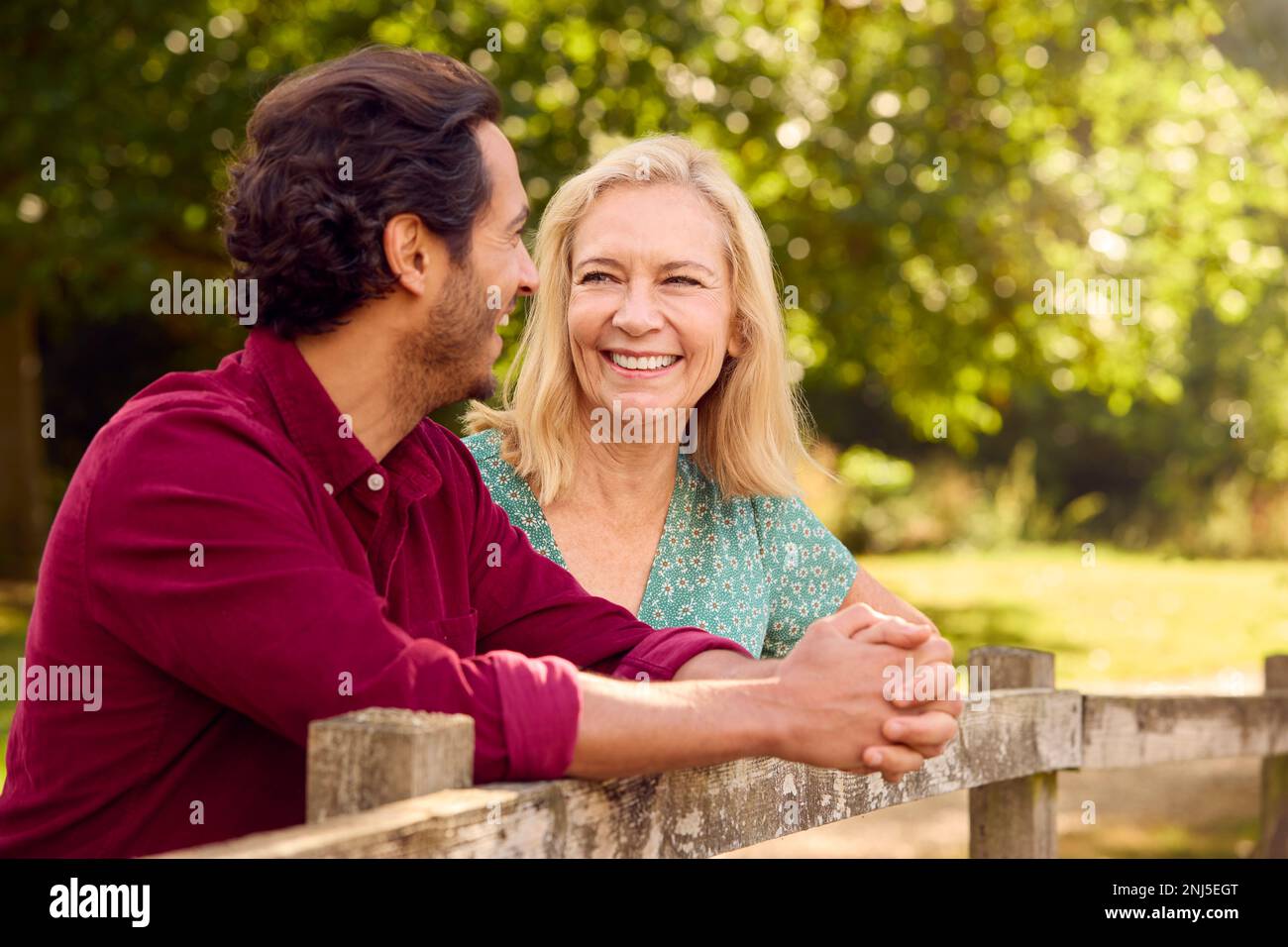 Mature Mother With Mixed Race Adult Son Leaning On Fence Walking In