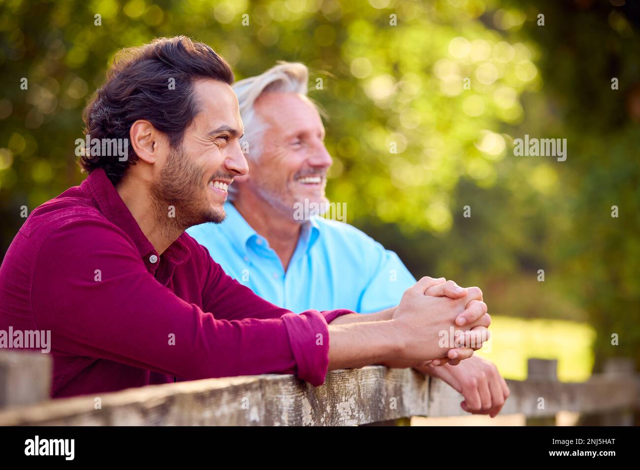 Mature Father With Mixed Race Adult Son Leaning On Fence Walking In