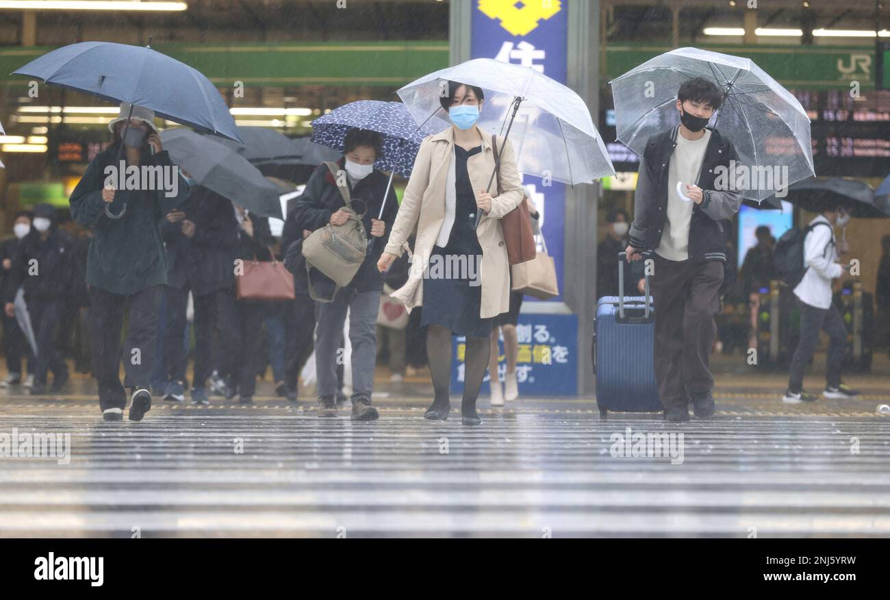 People wearing coats and jackets walk in cold rain near Shinjuku ...